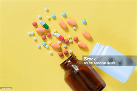 노란 배경에 알 약과 알 약 병 멀티 컬러 정제 및 알 약 캡슐 노란색 배경에 유리 병에서 다양 한 다양 한 약 정제 및 알