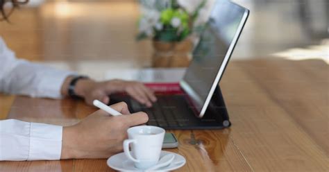 나무 테이블에 디지털 태블릿과 문구류로 작업 하는 여성 손의 측면보기 사진 Unsplash의 커피잔 이미지