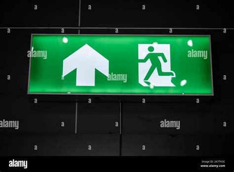 Big Emergency Fire Exit Sign Is Placed On The Black Wall Over The Door