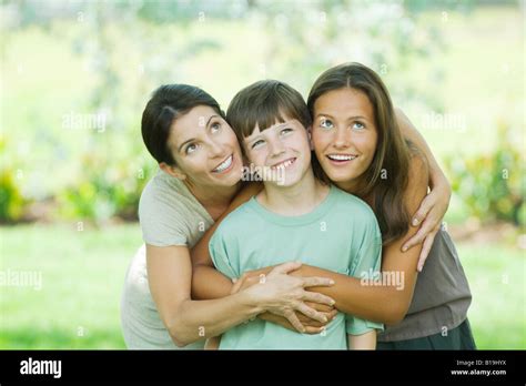 Mother Embracing Son And Teen Daughter All Smiling And Looking Up