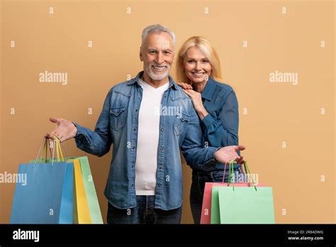 Happy Edlerly Couple Showing Their Purchases Beige Background Stock