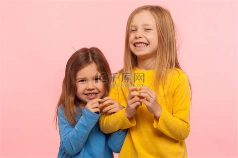 两个有趣的顽皮小女孩狡猾地看着镜头，一起策划棘手的计划高清摄影大图 千库网