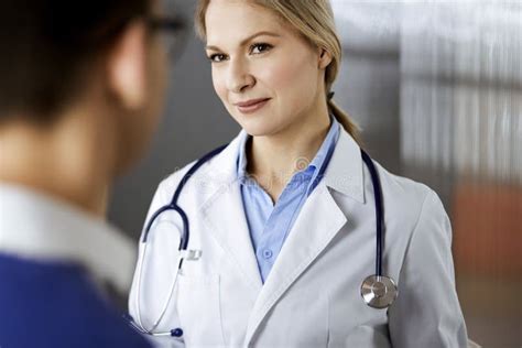 Friendly Female Doctor And Patient Man Discussing Current Health