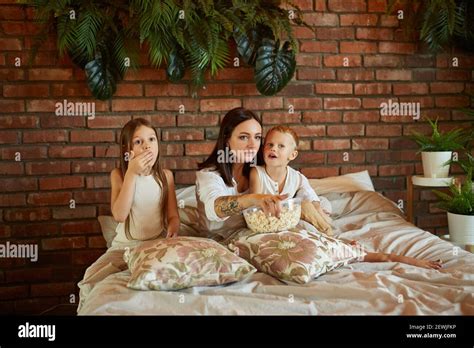 Maman Sassoit Sur Le Lit Avec Son Fils Et Sa Fille Et Regarde Un Film