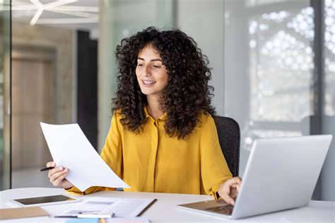직장에서 재무 보고서 및 계약을 확인하는 성공적이고 즐거운 여성 사무실에서 노트북을 사용하여 서류 작업을 하는 사업가 세금 양식을 준비하고 작성하는 금융가 25 29세에