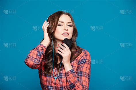 漂亮的年轻女孩在蓝色背景下摆姿势