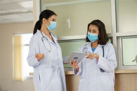 외과 용 얼굴 마스크를 착용하고 병원에서 태블릿 컴퓨터와 위로하는 다양한 의사 팀의 그룹 코로나바이러스 전염병 또는