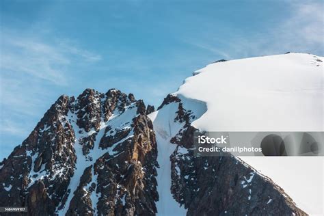 눈 덮인 산 꼭대기와 햇빛에 날카로운 바위가있는 미니멀리스트 고산 풍경 푸른 하늘에 눈 덮인 산이있는 단순한 미니멀리즘 매우 높은 고도에서 눈 산 정상에 대한 최소한의 전망