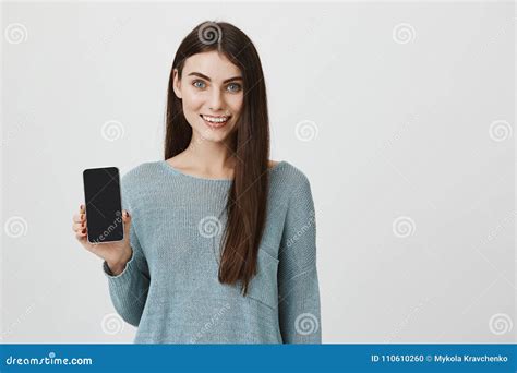 Изумительная и милая европейская женщина держа Smartphone в правой руке