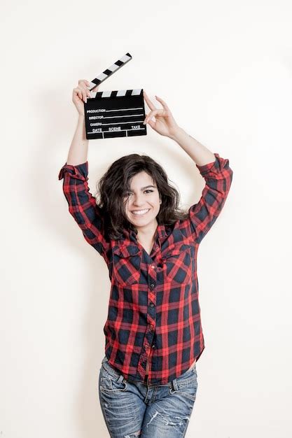 Retrato de uma mulher sorridente segurando um clapperboard de pé contra
