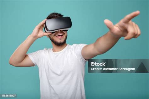 Vr 헤드셋을 시도 하 고 손가락을 대 고 매력적인 수염 남자 화려한 배경에 가상 현실 고글과 함께 다른 세계를 탐험 하는 젊은