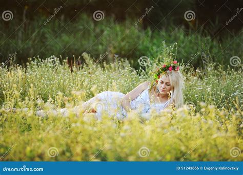 Girl In A White Sundress And A Wreath Of Flowers On Her Head Sit Stock