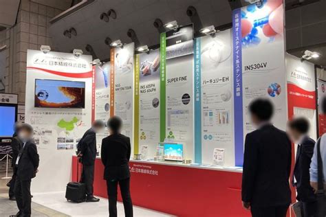 People Are Standing In Front Of A Display At An Event With Posters On