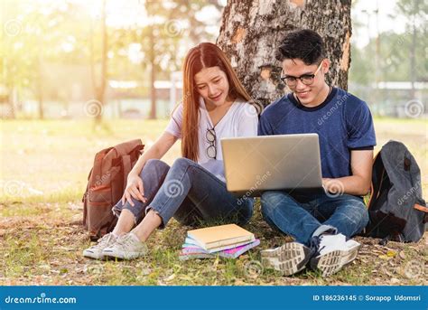 Young Man And Girls Friend Classmates Sitting At Park Under Tree Stock