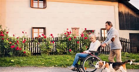 개와 함께 산책하는 노부부 마을 길에서 휠체어를 탄 여성을 밀고 있는 노인 사진 Unsplash의 성인 이미지