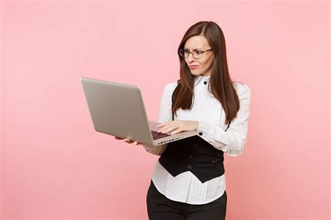 젊은은 노트북 Pc 컴퓨터 파스텔 핑크 바탕에 고립에서 일 하는 안경에 불만족된 비즈니스 여자를 자극 여자 보스입니다 성과 경력