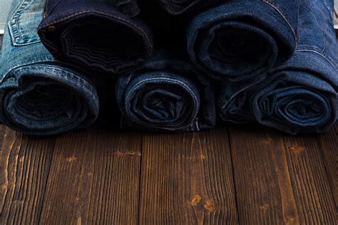 롤 Frayed 청바지 또는 청바지 데님 컬렉션에 거친 어두운 나무 테이블 배경 복사 공간 오래 된 패션 개념 갈색에 대한 스톡
