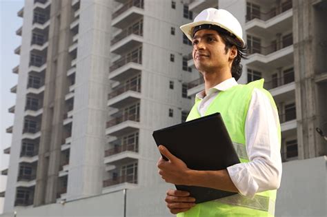 건설 노동자의 헬멧을 쓰고 건축업자의 재산 앞에 서 있는 행복한 인도 건설 노동자의 초상화 개발에 대한 스톡 사진 및 기타 이미지 Istock