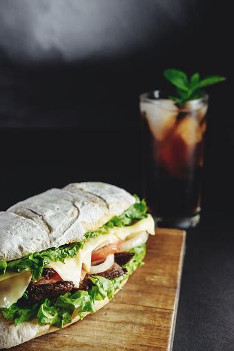 검은 배경 로즈마리 오이 나무 보드 길거리 음식에 몇 가지에 대 한 큰 샌드위치 패스트푸드 쇠고기와 함께 수 제 햄버거 나무 테이블에 치즈 얼음 콜라의 유리 민트 0명에