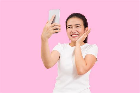 귀여운 아시아 여자 Selfie 복용 스마트 휴대 전화 카메라 아름 다운 게시 멋진 미소 소셜 미디어 십 대 소녀 흰 셔츠 핑크