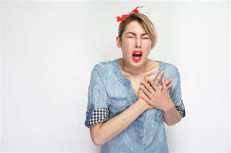 심장 마비 메이크업과 빨간 머리 띠를 가진 우연한 파란 데님 셔츠에 있는 젊은 여자의 초상화 비명을 내 고 그녀의 고통 스러운