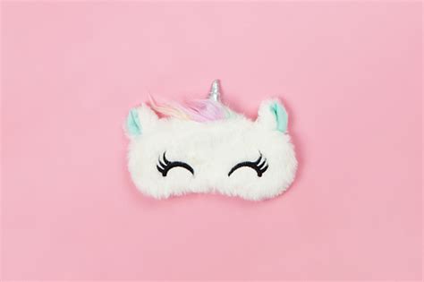 파스텔 핑크 종이 배경 복사 공간에 닫힌 눈과 작은 귀를 가진 흰색 푹신한 모피 수면 마스크 유니콘 상단보기 평평한 누워 생생한 꿈의 개념 여자와 젊은 여성을위한 액세서리