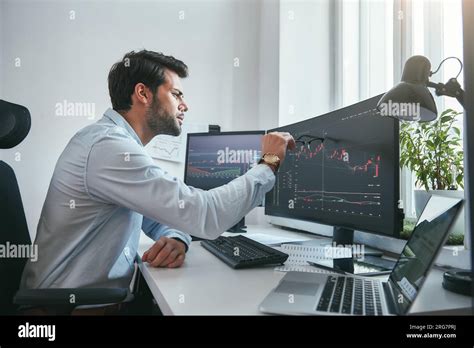 Analyzing Data Thoughtful Young Trader Is Pointing At Graphs On