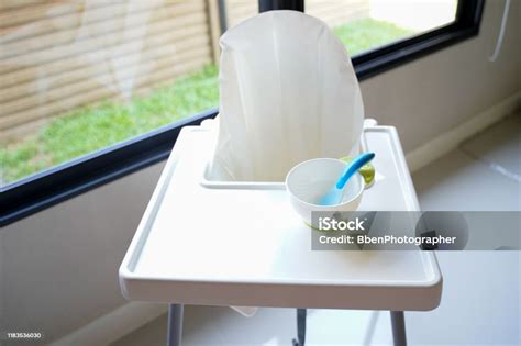 집안의 창문 옆에 흰색 높은 의자를 닫고 파란색 숟가락이있는 빈 흰색 그릇이 유아 식사 아기 먹이 개념을 위해 준비됩니다 유아용 식탁의자에 대한 스톡 사진 및 기타 이미지