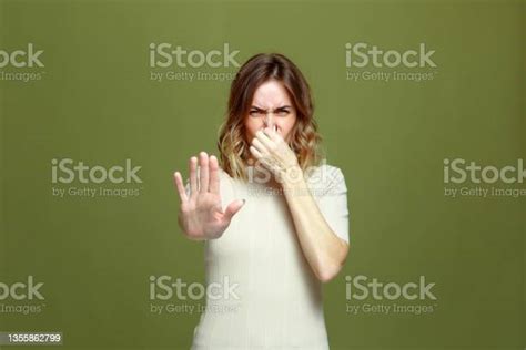 나쁜 냄새 어린 소녀는 중지 제스처를 보여주는 코를 꼬집고 녹색 배경에 혐오감을 느낍니다 독성 냄새 끔찍한 향수 불쾌한 냄새에