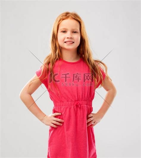童年和人的概念 微笑的红发女孩穿着粉红色的裙子在灰色的背景下摆姿势。高清摄影大图 千库网