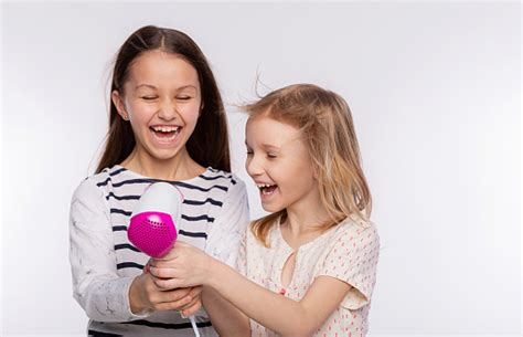 68 세의 두 명의 아름다운 소녀가 헤어 드라이어와 놀고 있습니다 여자 장난 지출 시간 함께 하 고 흰색 배경 위에 머리를 건조 2명에 대한 스톡 사진 및 기타 이미지