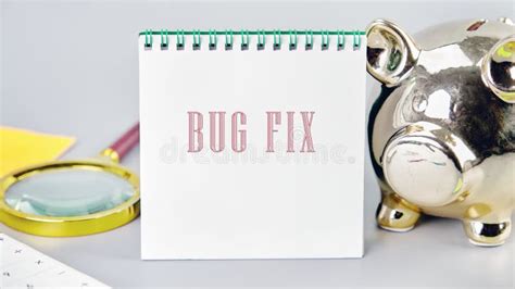 A Notepad Displaying Bug Fix Prominently Sits Near A Shiny Piggy Bank And A Magnifying Glass On