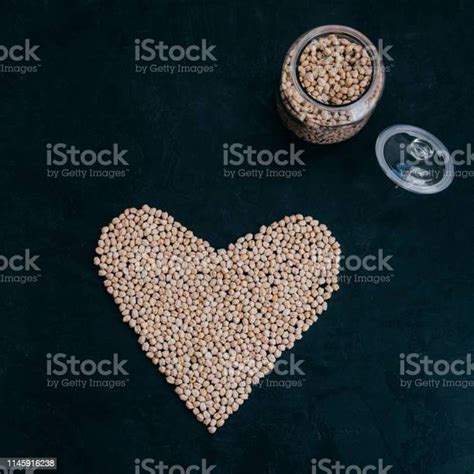 유리 항아리에 마른 깨끗 한 병아리 콩 유기농 생가 르 반 조로 만든 심장 검정색 배경입니다 식물 기반 단백질 건강 한 요리를 만들기 위한 콩 0명에 대한 스톡 사진 및
