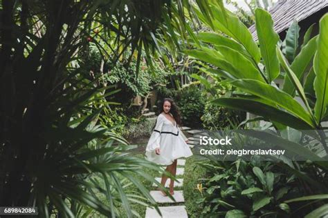 하얀 드레스를 입고 열 대 정원을 산책 하는 여자 긴 검은 머리와 갈색 머리입니다 패션 튜 닉 맨발 자연 즐기기 갈색 머리에 대한 스톡 사진 및 기타 이미지 Istock