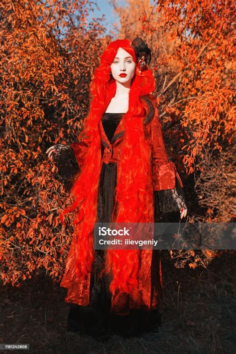 고딕 할로윈 코트입니다 가을 배경에 젊은 중세 여왕입니다 빨간 머리를 가진 여자 창백한 피부뱀파이어 할로윈을위한 중세 의상 고딕 양식의 드레스를 입은 환상적인 여왕 뱀파이어