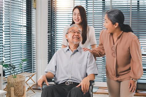 행복한 가족 아시아의 젊은 딸과 어머니는 노인을 지원합니다 아름다운 소녀는 집안의 거실에서 건강을 위해 물리 치료를하는 노인