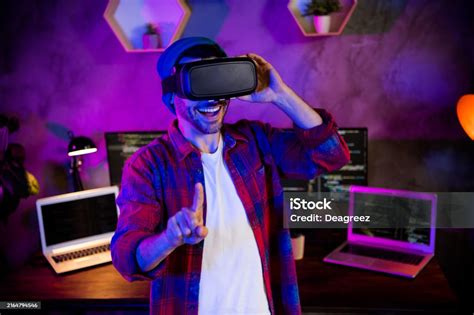 Photo Of Funny Smiling Coder Dressed Hat Eyewear Teating 3d Game Modern Gadget Indoors Workplace