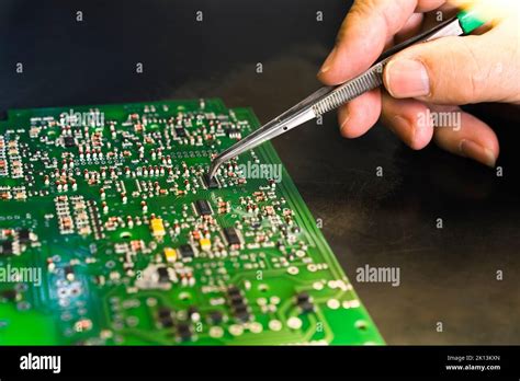 Person Repairing Printed Circuit Board PCB Mounting Electrical Components By Hand Using Tweezers