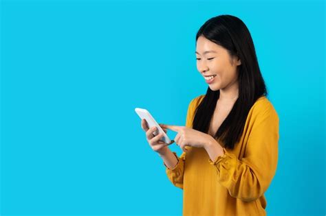 Premium Photo Cheerful Chinese Woman Using Cell Phone On Blue Copy Space