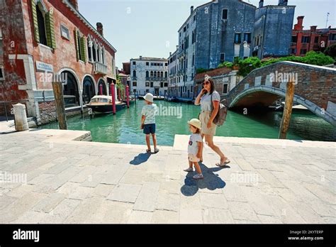 Mother With Son And Daughter Walking Near Bridge Canal In Venice Italy