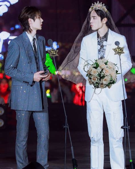 Two Men Standing Next To Each Other In Front Of Microphones