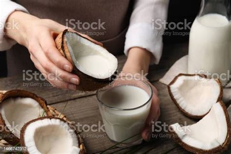 나무 테이블에서 비건 우유와 함께 유리 근처에서 맛있는 코코넛을 들고 있는 여자 근접 촬영 건강한 생활방식에 대한 스톡 사진 및