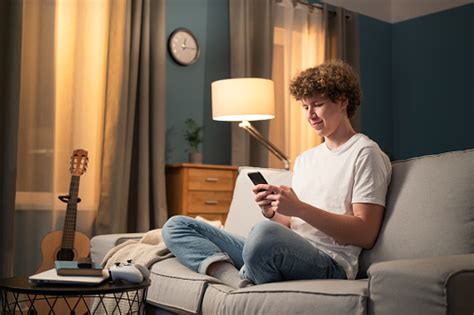 Скучающий Мальчик Подросток Школьник Студент Отдыхает На Диване Вечером Со Своим Телефоном