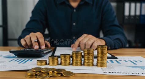 Man Calculating Finances With Calculator And Stacks Of Coins On A