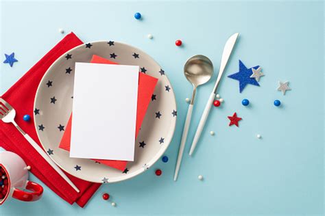 미국의 독립 기념일을 축하하기 위해 꾸며져 있는 테이블의 평면도 애국적인 요소로 장식된 접시 컵 수저 냅킨 별 파스텔 블루 배경