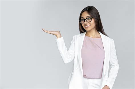 열린 손바닥에 보이지 않는 물체 복사 공간을 들고 공식적인 착용 정장에 젊은 성인 인도 사업가 미소 복사 공간이있는 회색 배경에