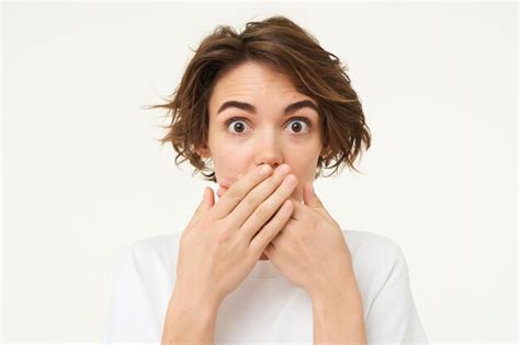 Изображение брюнетки закрывающей рот выглядит удивленной прижимающей руки к губам стоит над
