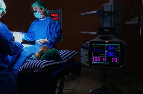 병원 수술실에서 구조 환자에 대한 심박수를 보여주는 Ecg Ekg 모니터와 함께 직장에서 수술을 수행하는 의료 팀 외과 의사