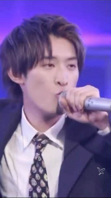A Man In A Suit And Tie Singing Into A Microphone