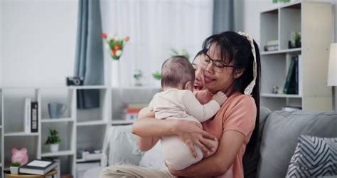 Handheld Shot Asian Mother Sit On The Sofa Holding Her Little Son In